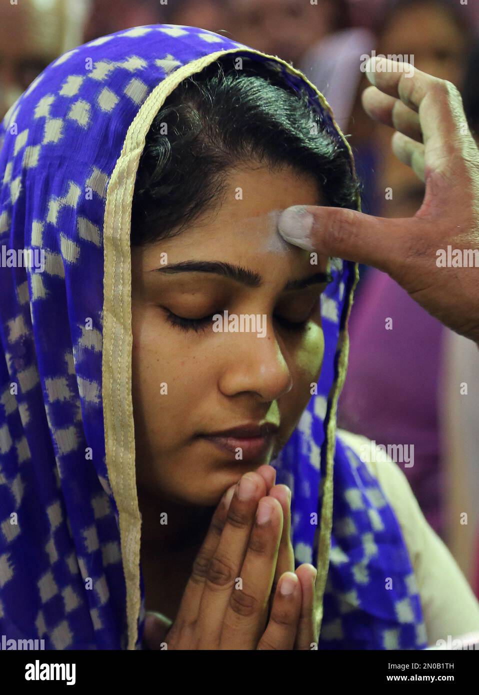 A Roman Catholic priest marks a sign of the cross on the forehead of an ...