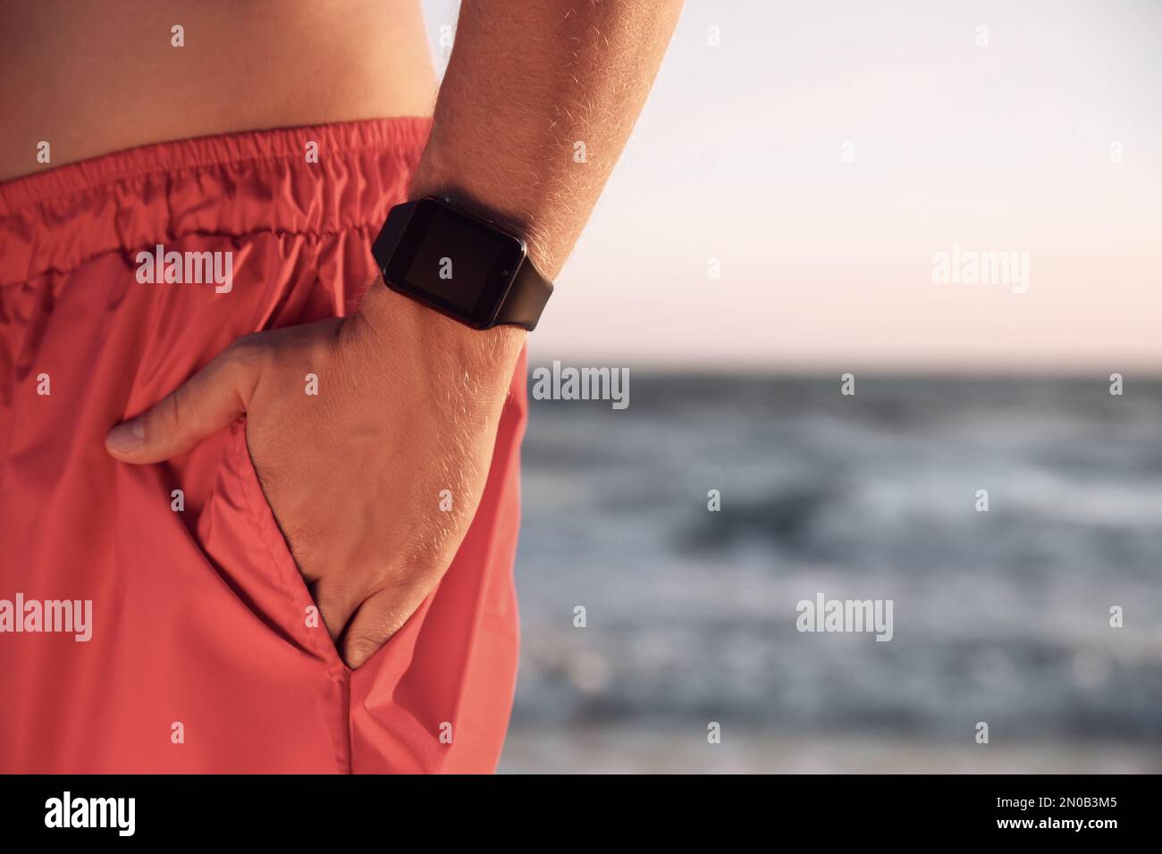 Man wearing smart watch on beach at sunset, closeup Stock Photo - Alamy