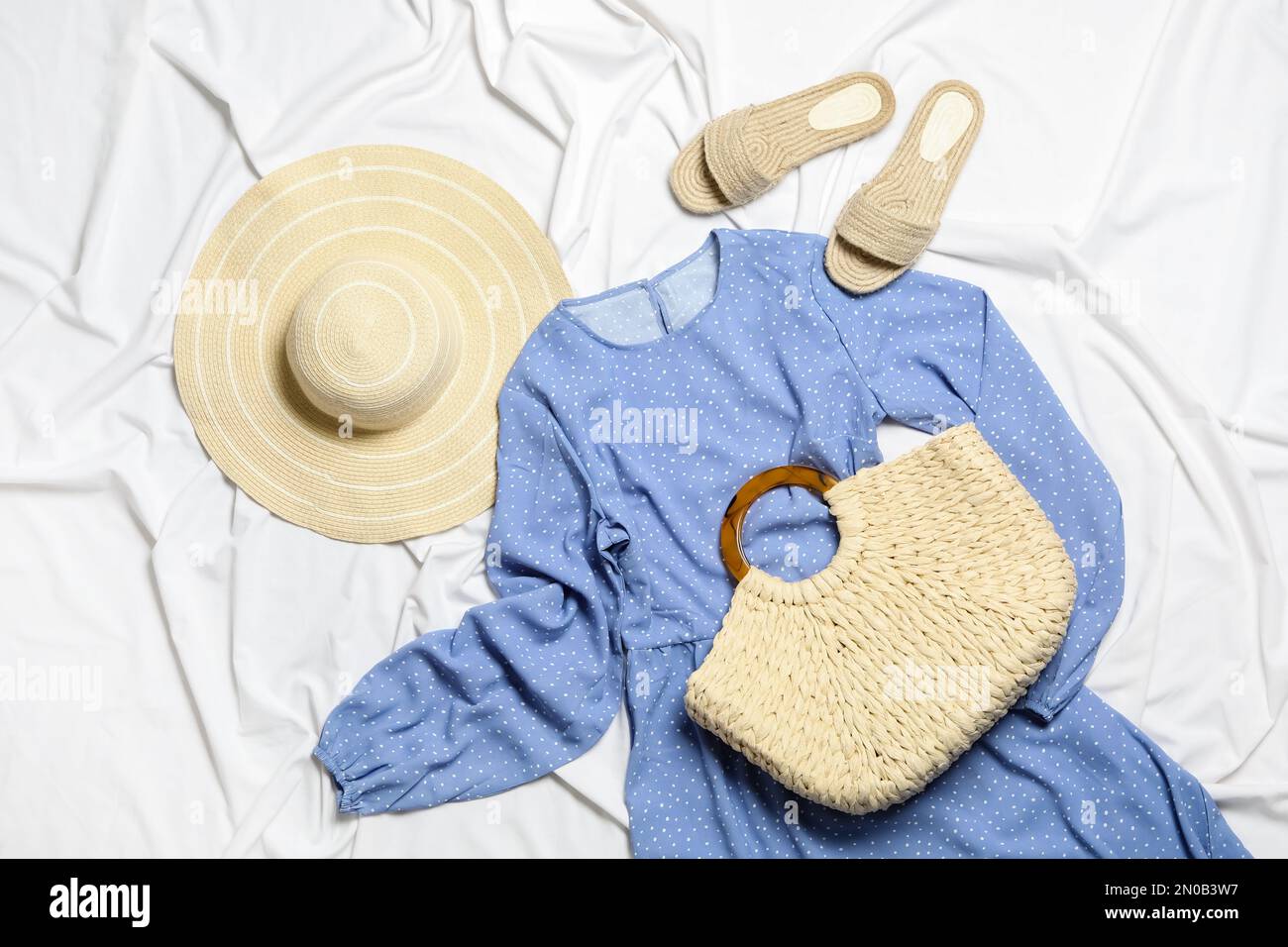 Flat lay composition with stylish light blue dress on white fabric ...