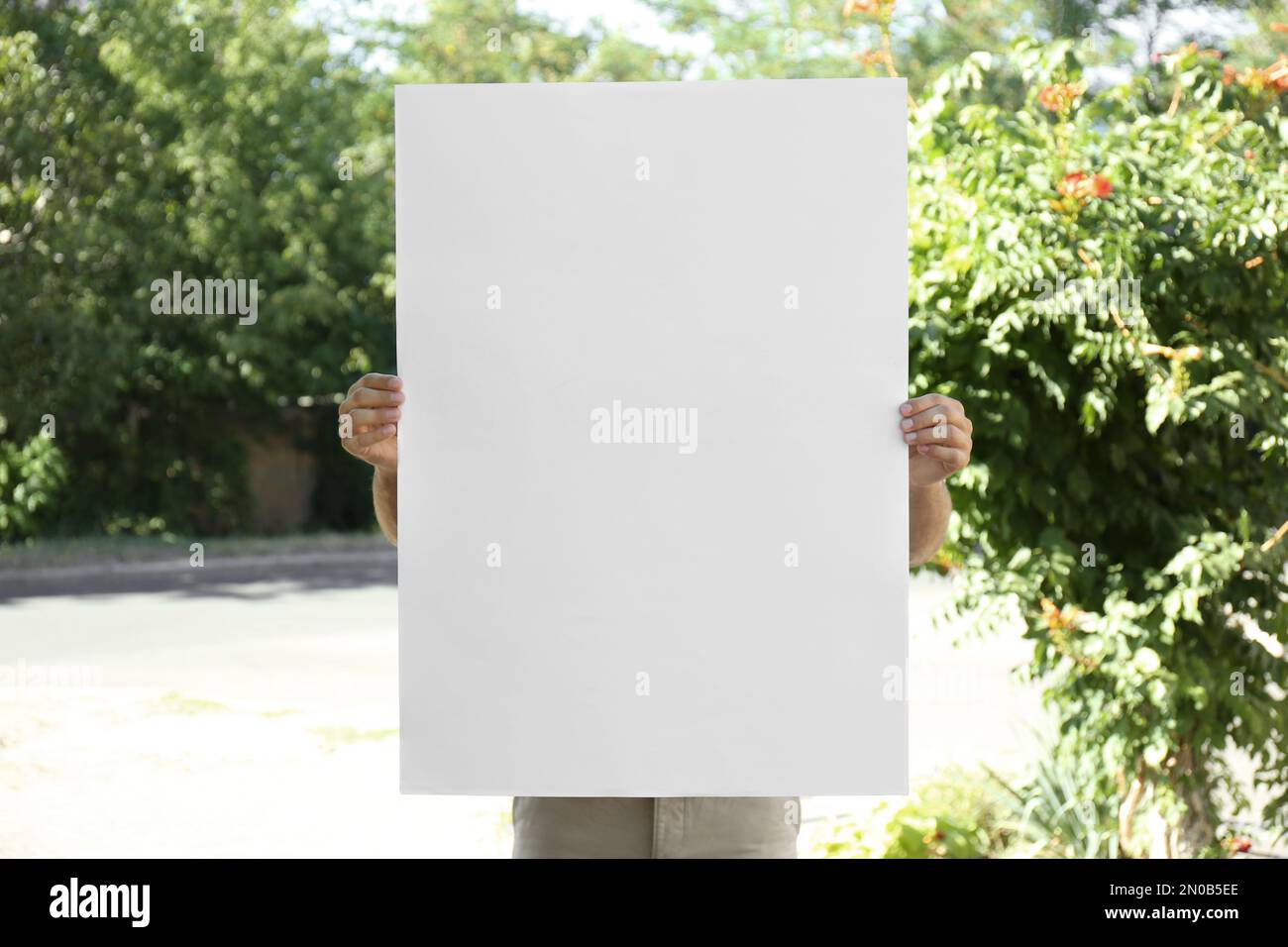 Man holding white empty poster outdoors. Space for design Stock Photo ...