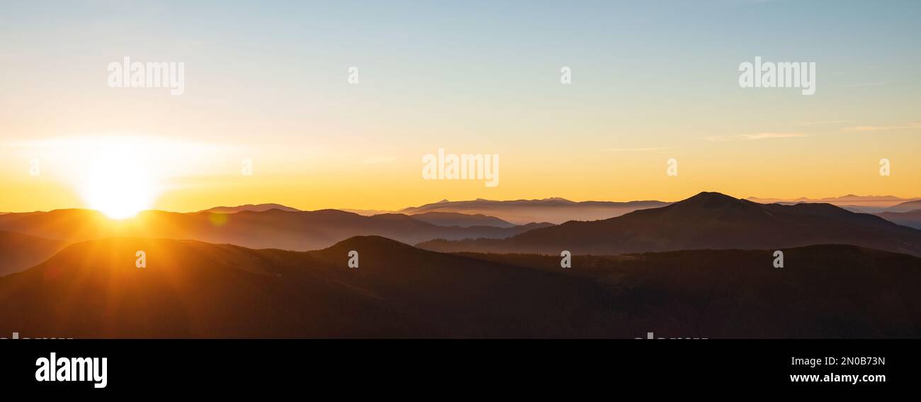 Mountain sunrise header. Mountain silhouettes and rays of the rising ...