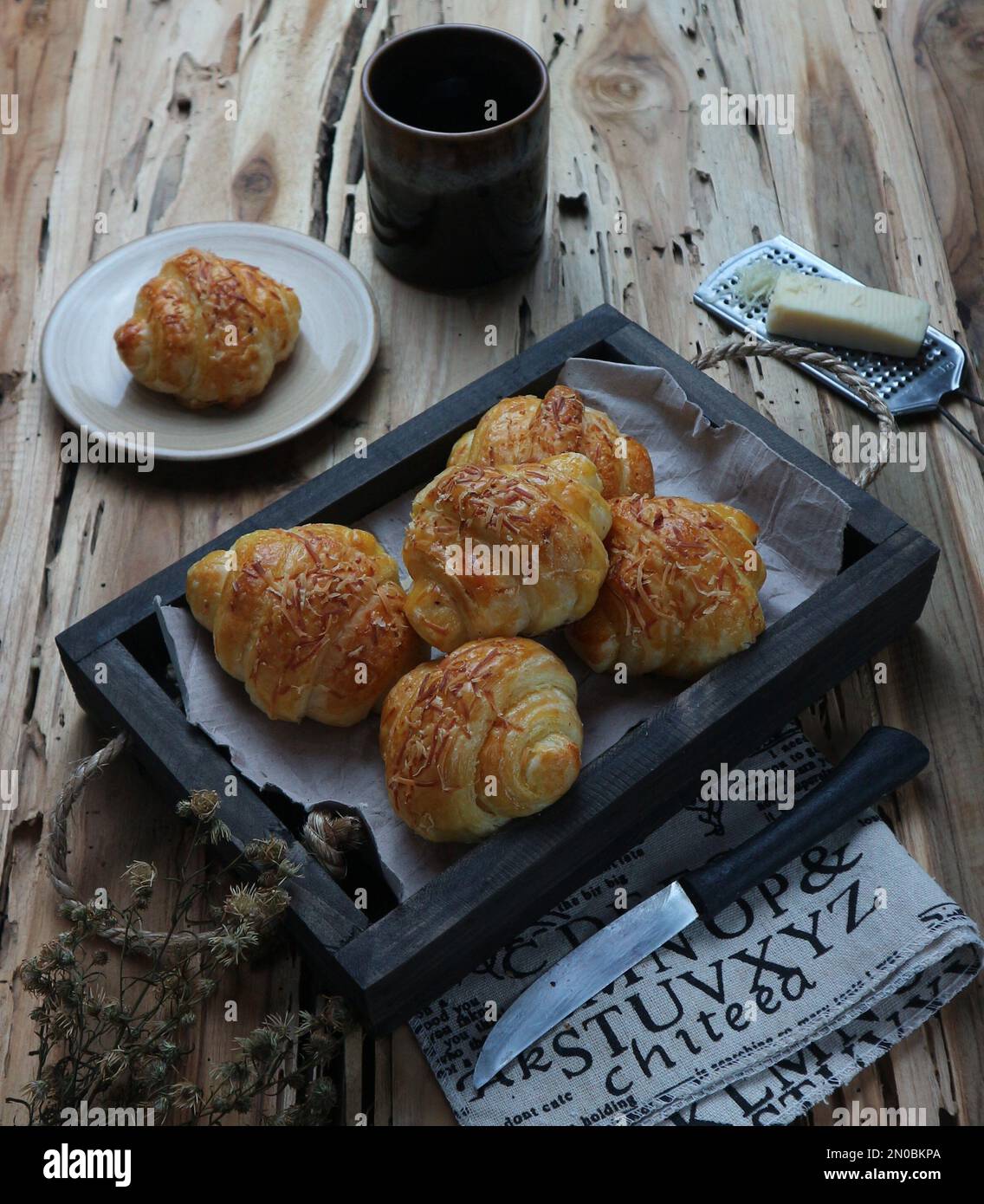 Homemade mini croissants on a black wooden tray with cups and saucers ...