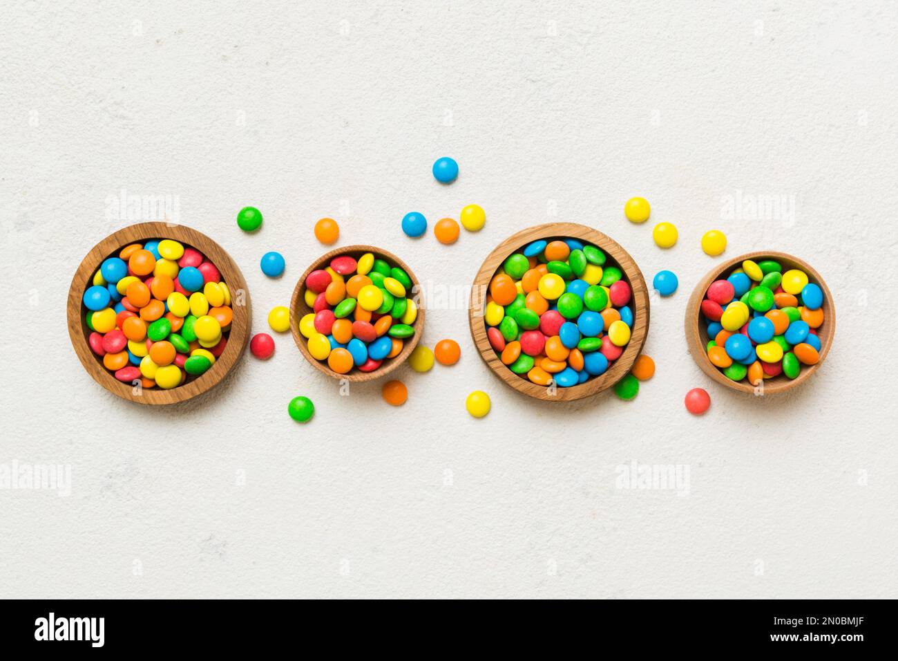 different colored round candy in bowl and jars. Top view of large ...