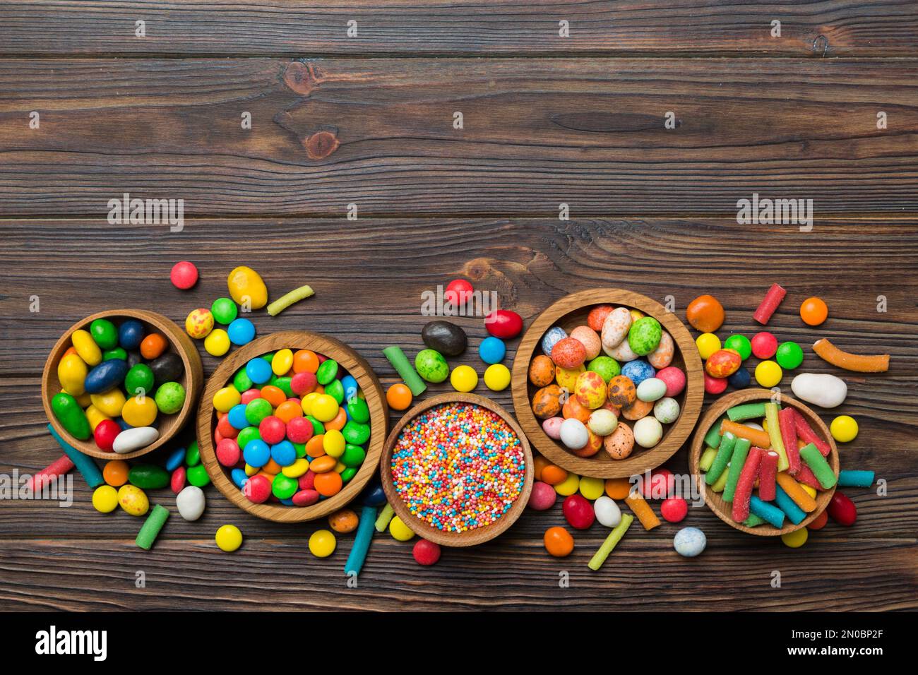 different colored round candy in bowl and jars. Top view of large ...