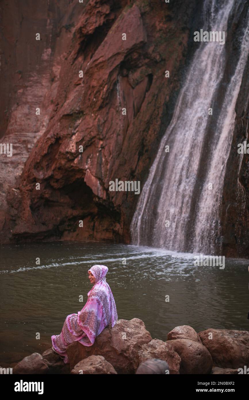 A tourist poses for a photo in front of the Oum Rabia Waterfalls of ...