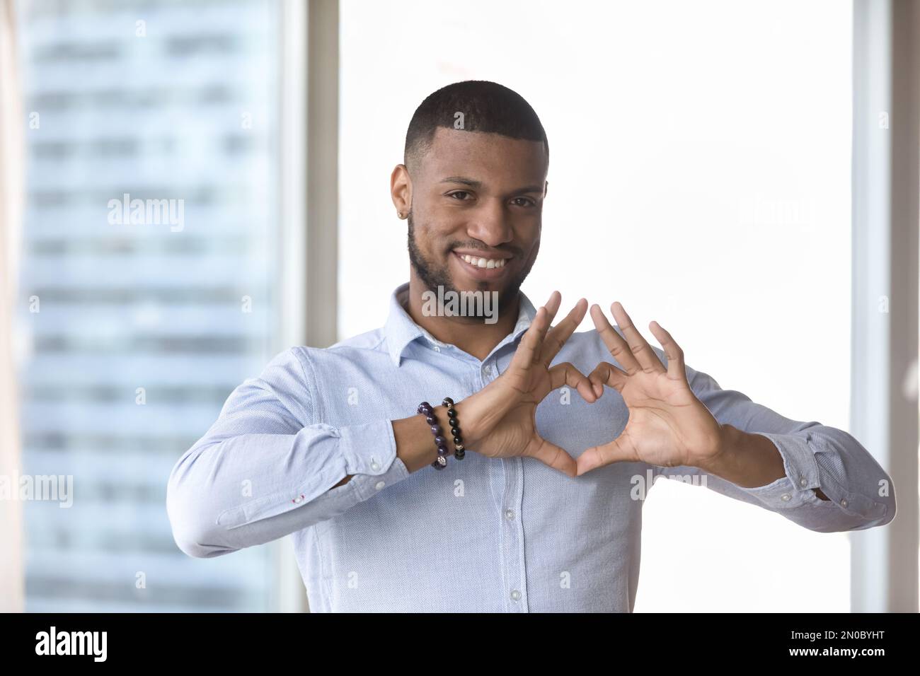 Happy handsome young man making hand heart at chest Stock Photo - Alamy