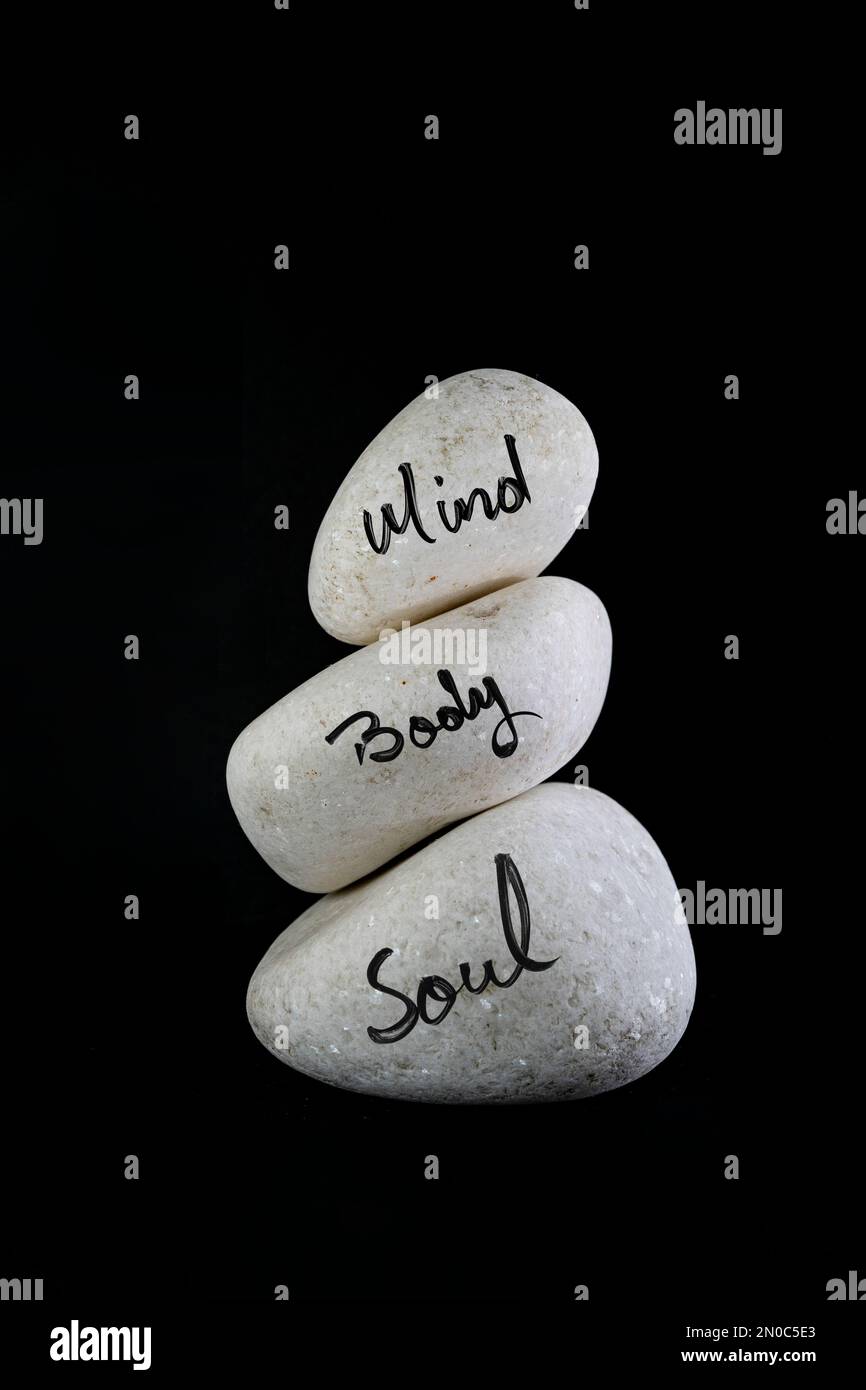 3 white stones stacked, with mind body and soul hand written, isolated ...