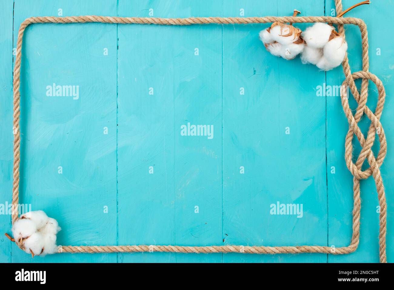 Jute rope rectangular frame, with a knot and cotton flowers, on blue ...