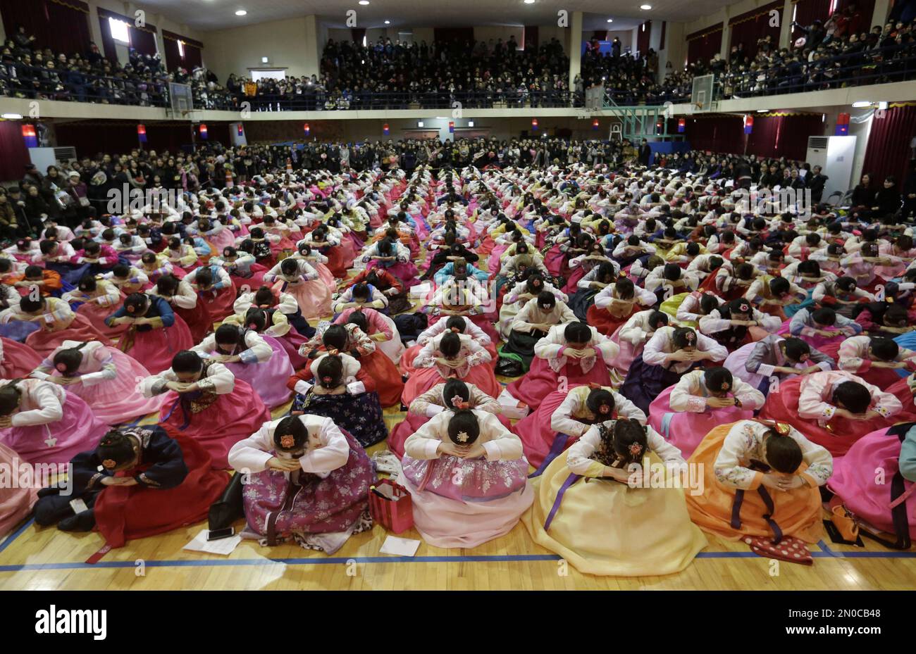 South Korean senior students clad in traditional costumes sit and bow ...