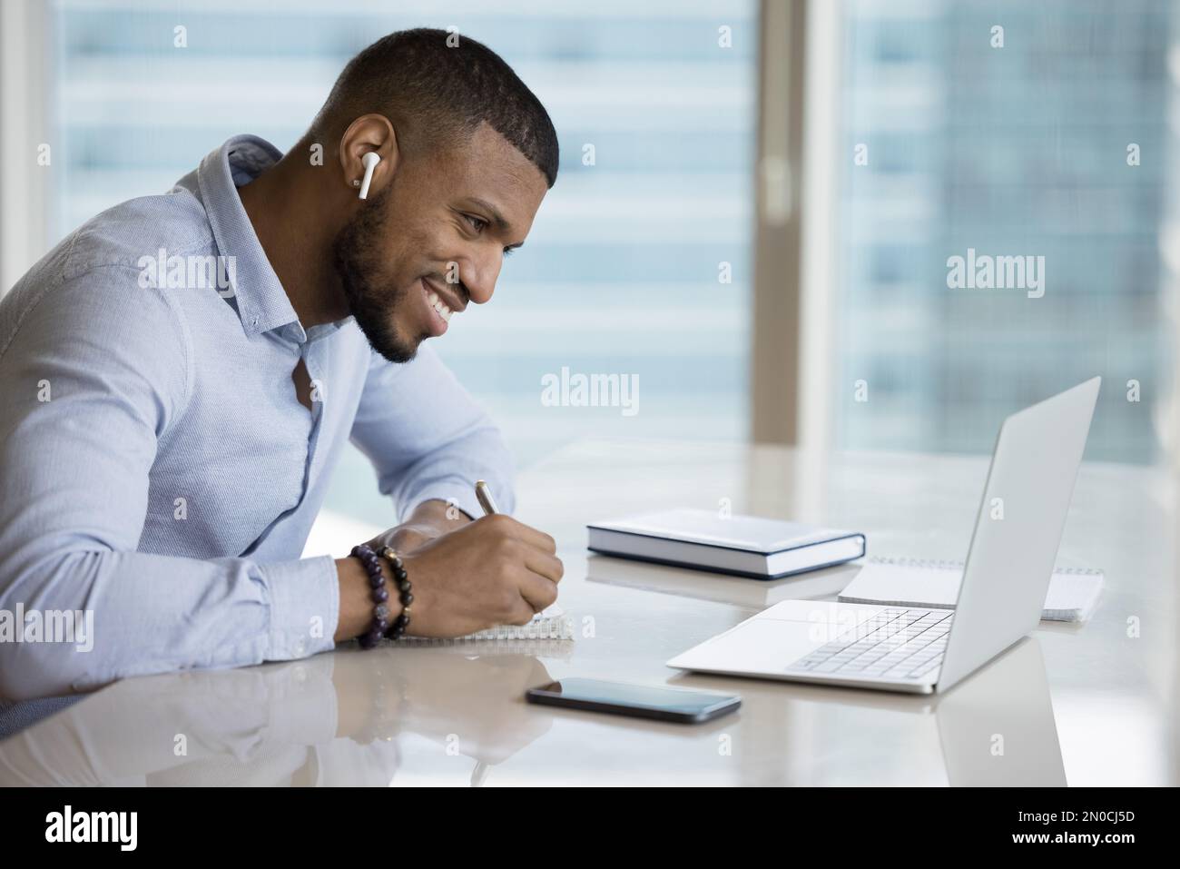 Happy employee studying new skills, using wireless earphone in ear ...