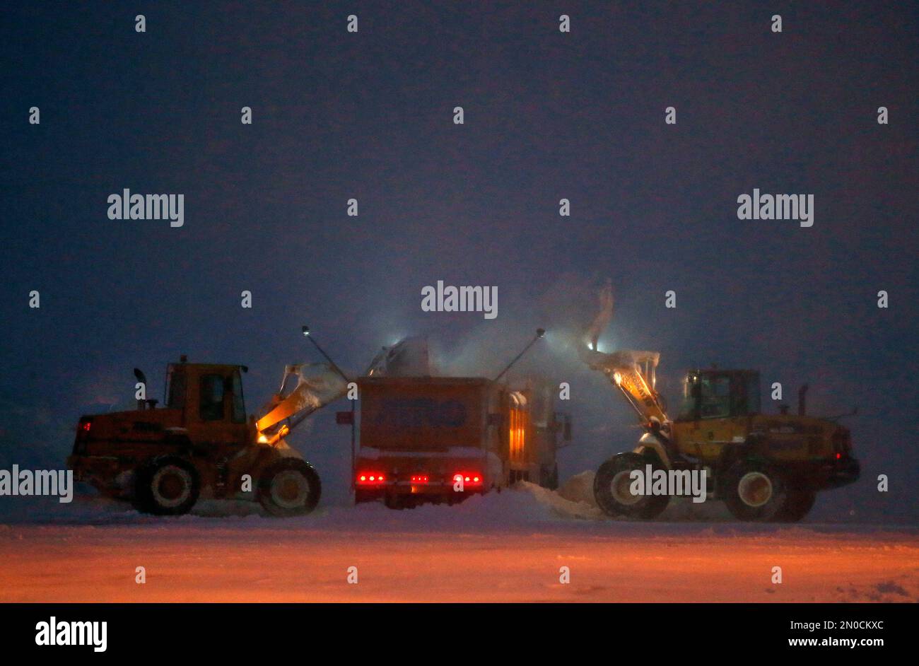 Front end loaders move snow into a giant snow melting truck snow during ...