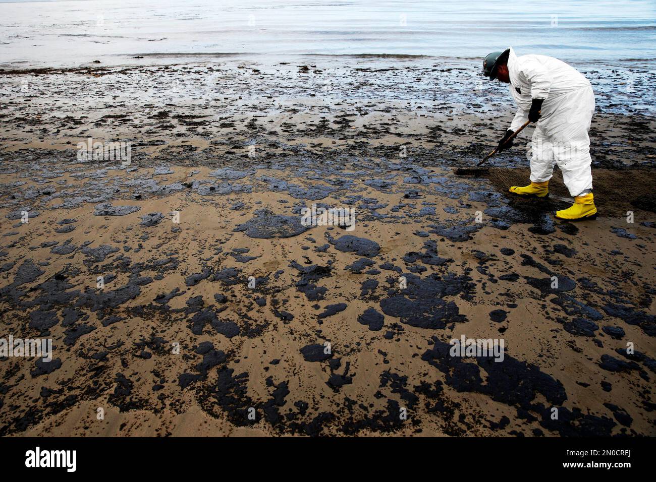 FILE - In this May 21, 2015, file photo, a worker removes oil from sand ...