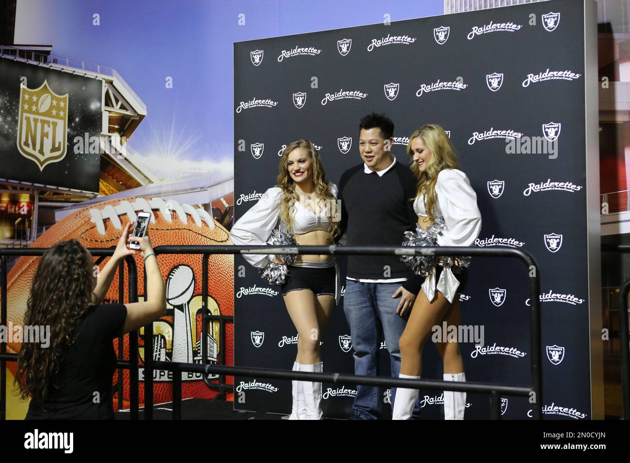 An NFL fan takes a photo with Raiders cheerleaders at a display in the ...