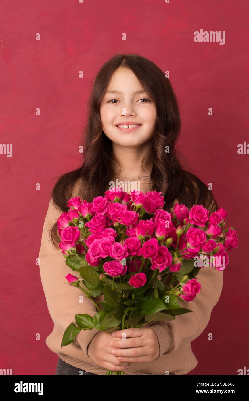 A teenage girl with a bouquet of beautiful pink roses on a pink ...