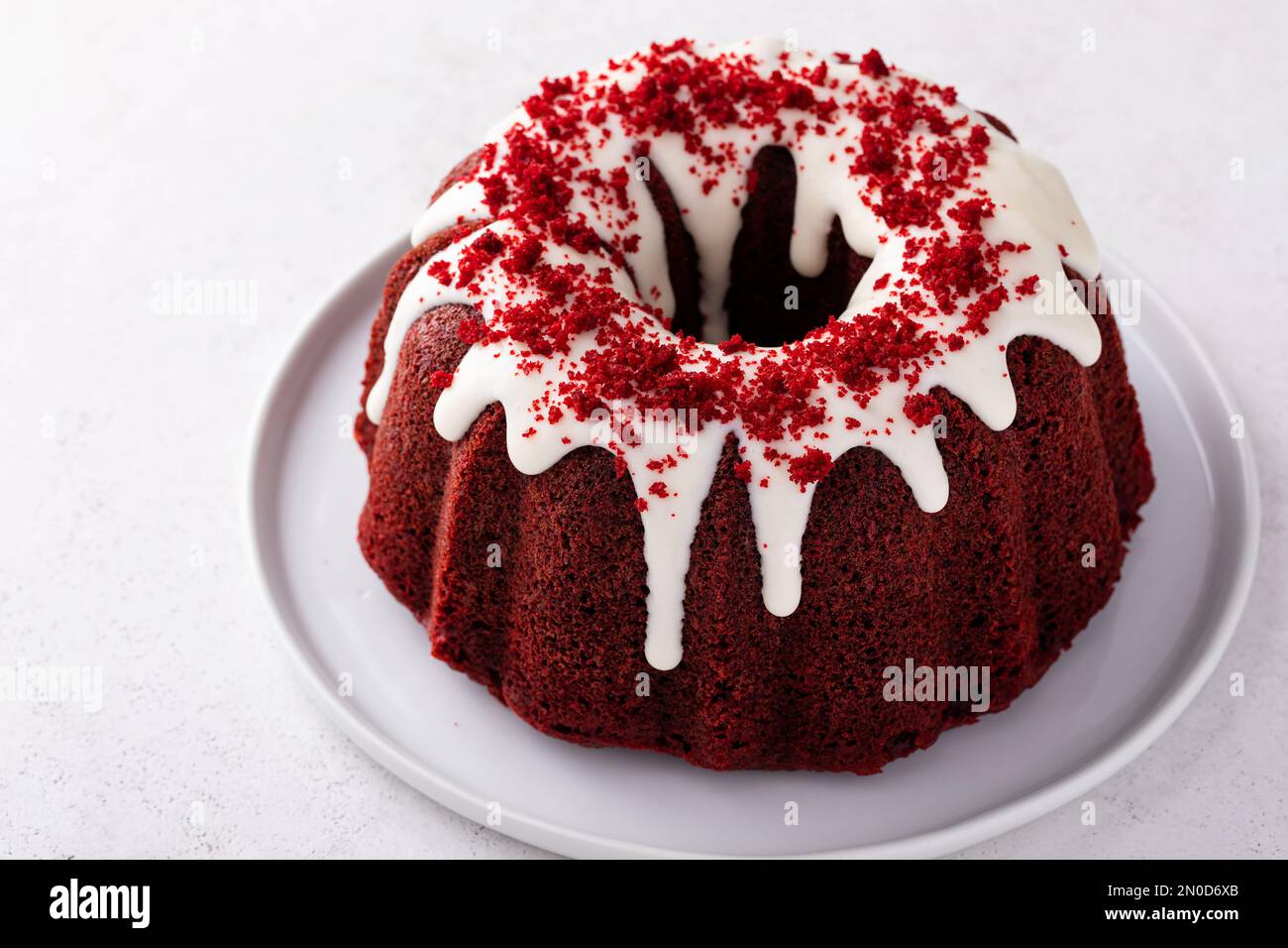 Red velvet bundt cake with cream cheese frosting and cake crumbs on top ...