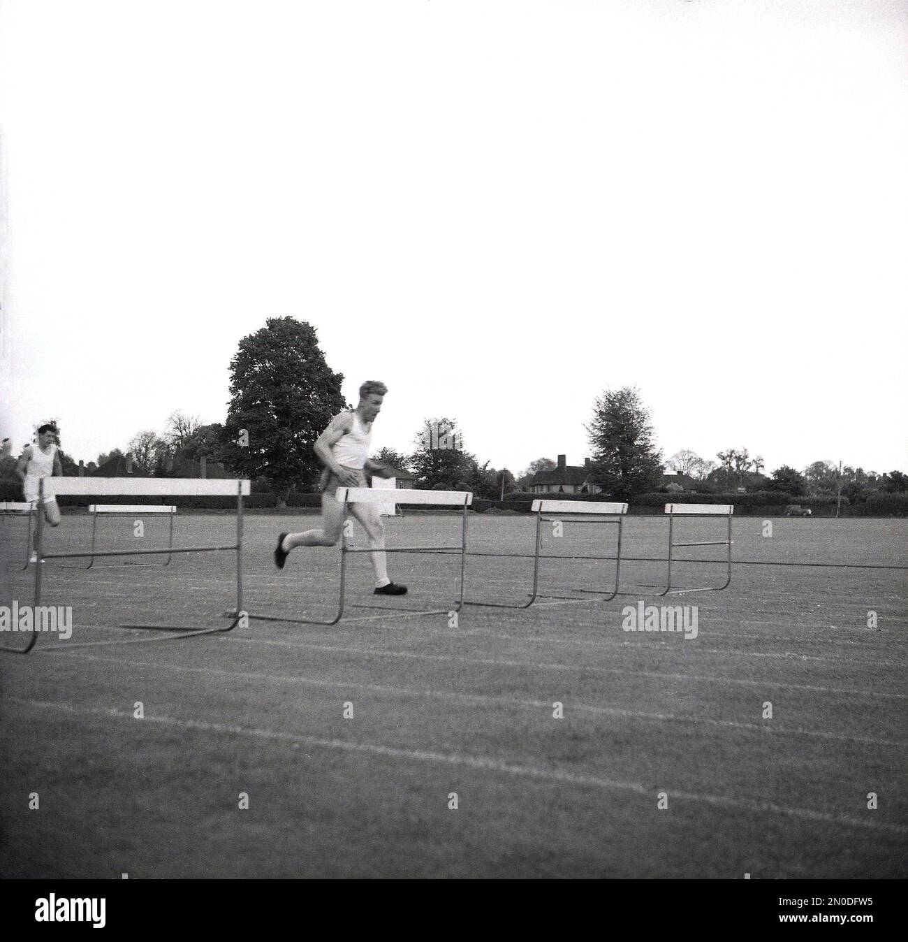 1950s, historical, two young male athletes taking part in a hurdles ...