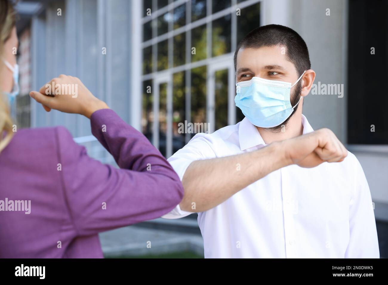 Man and woman bumping elbows to say hello outdoors. Keeping social ...
