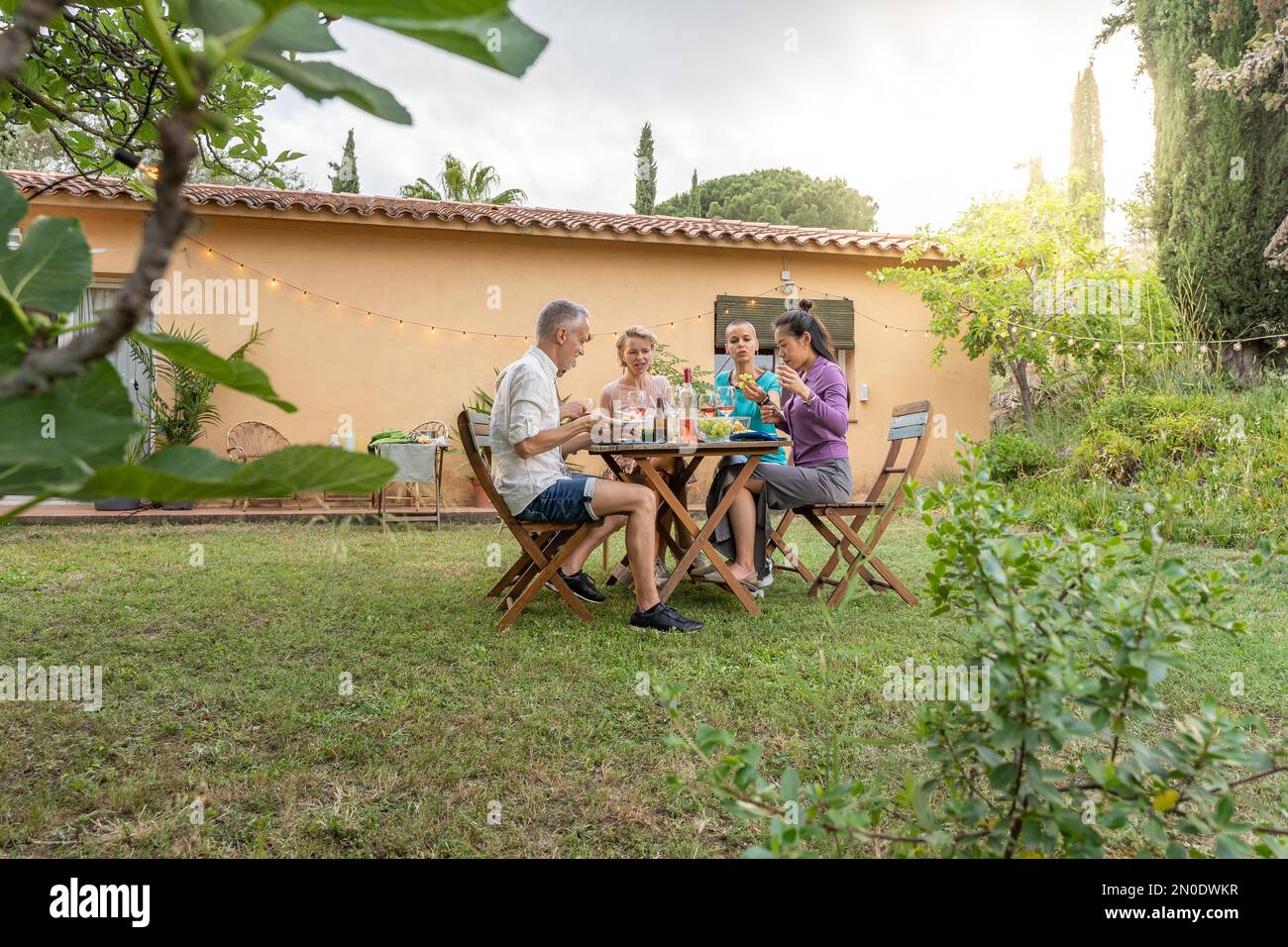 Middle-aged men and women eating healthy food at country house yard ...