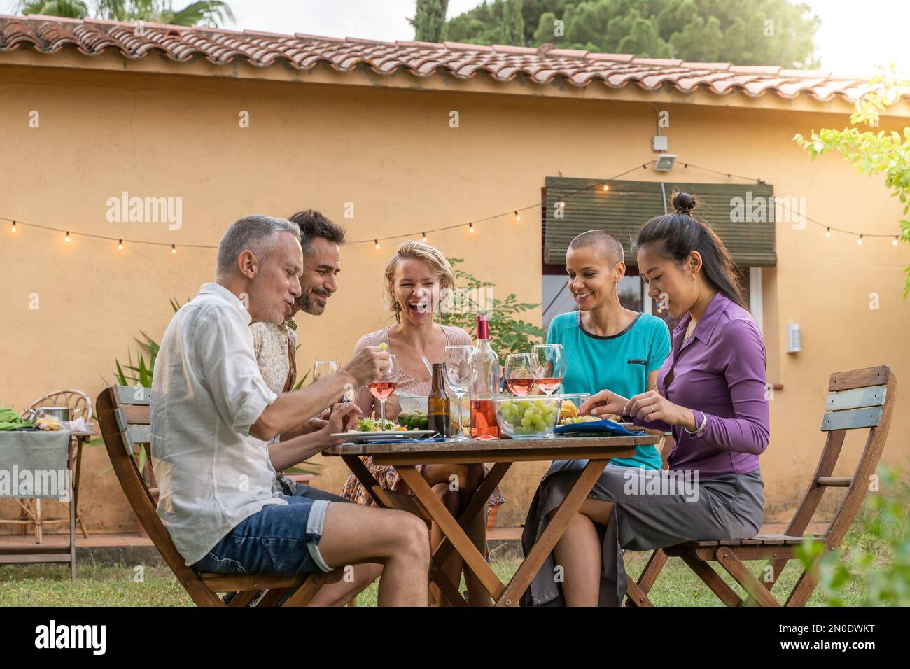 Happy middle-aged men and women eating healthy food at country house ...