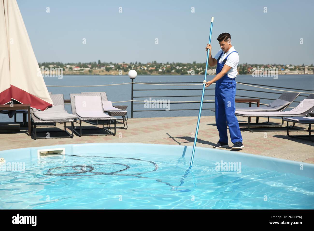 Worker cleaning outdoor swimming pool with underwater vacuum Stock ...