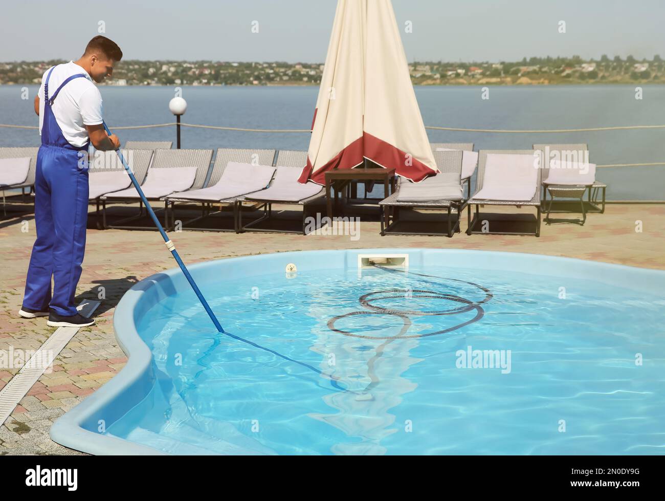 Worker cleaning outdoor swimming pool with underwater vacuum Stock ...