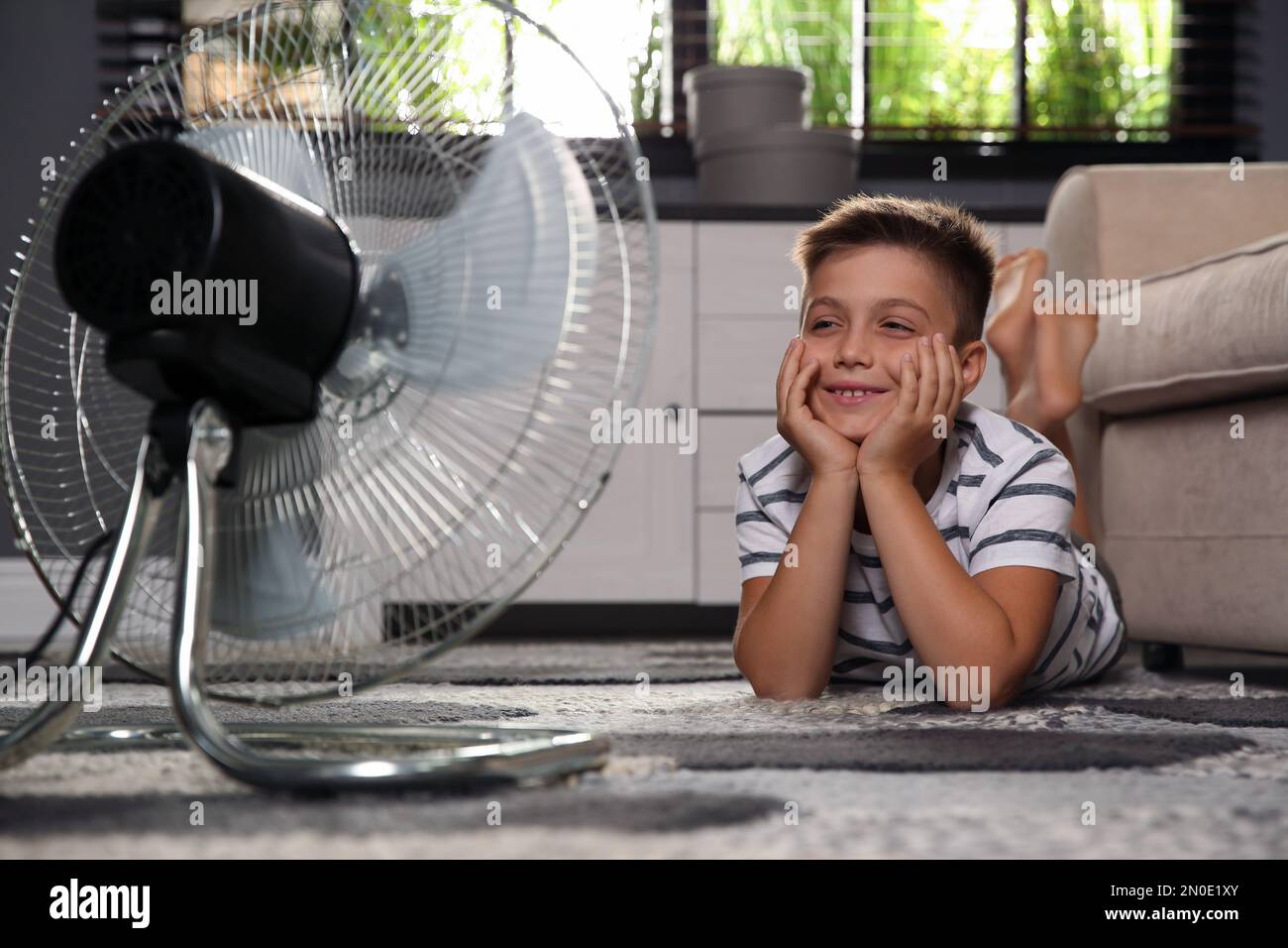 Little boy enjoying air flow from fan at home. Summer heat Stock Photo ...