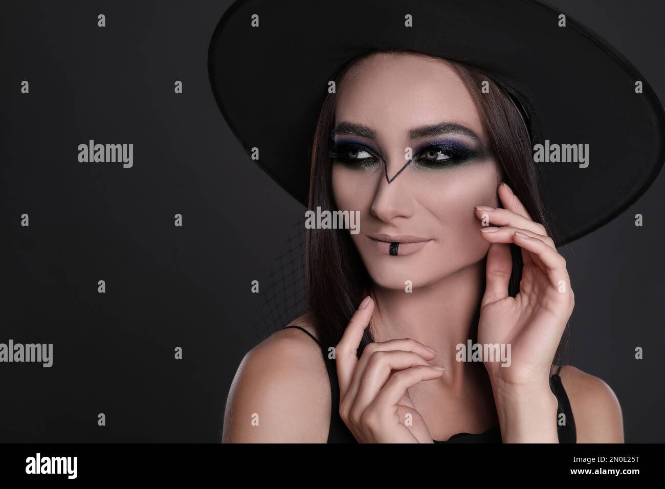 Mysterious witch wearing hat on black background, closeup Stock Photo ...