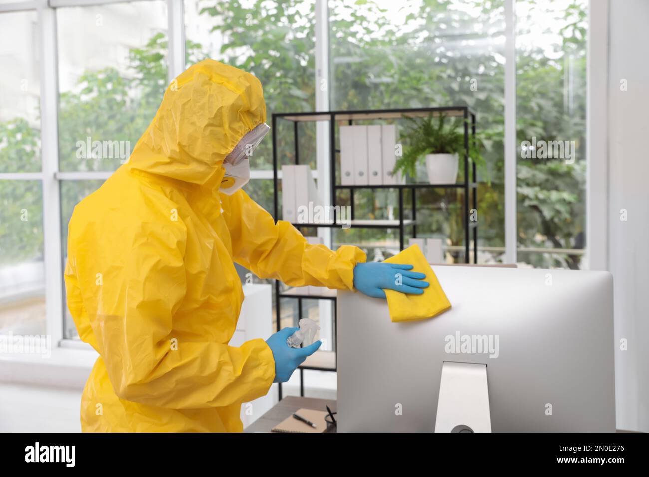 Janitor disinfecting computer in office to prevent spreading of COVID ...