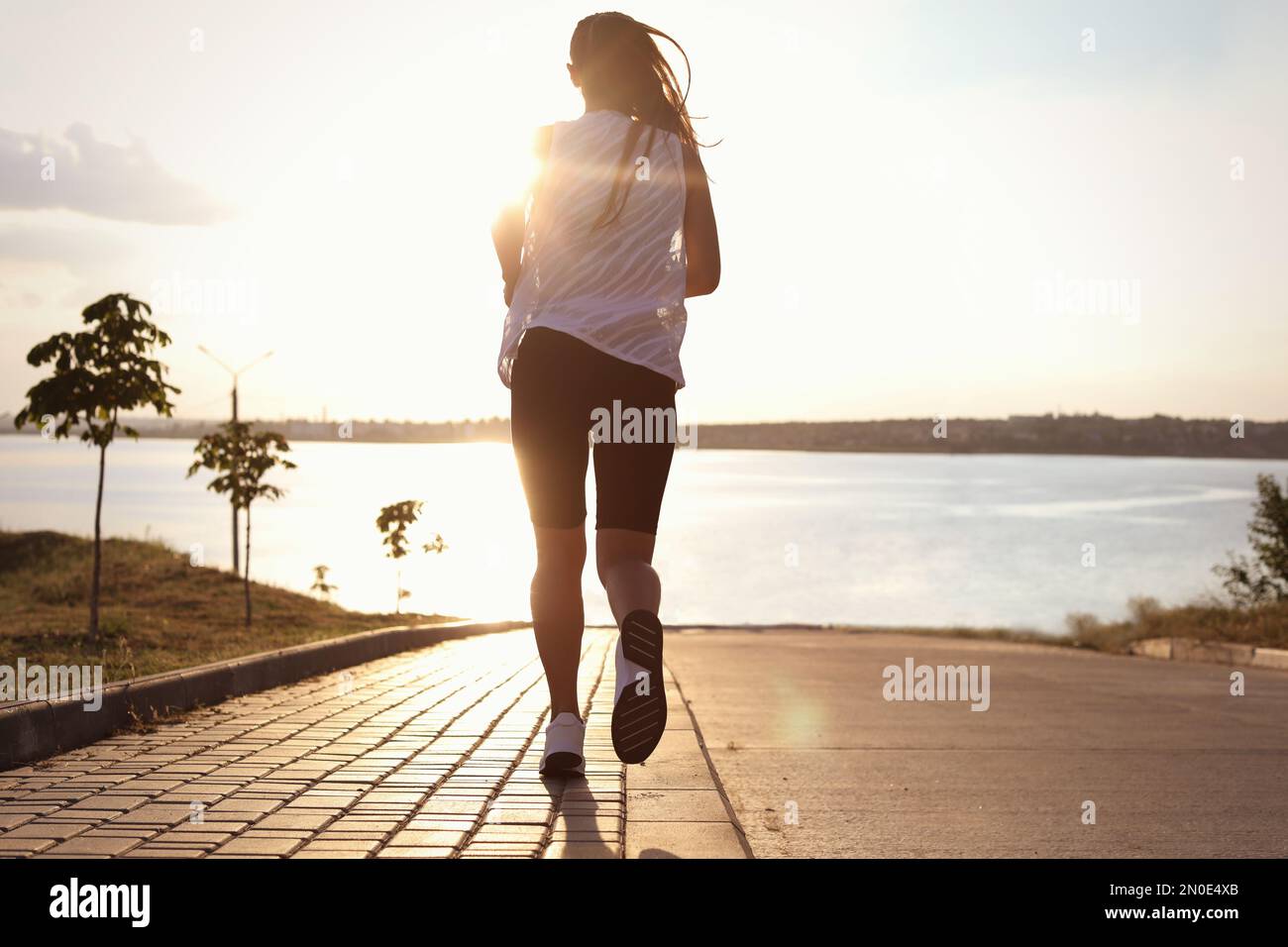 Young woman running near river in morning, back view Stock Photo - Alamy