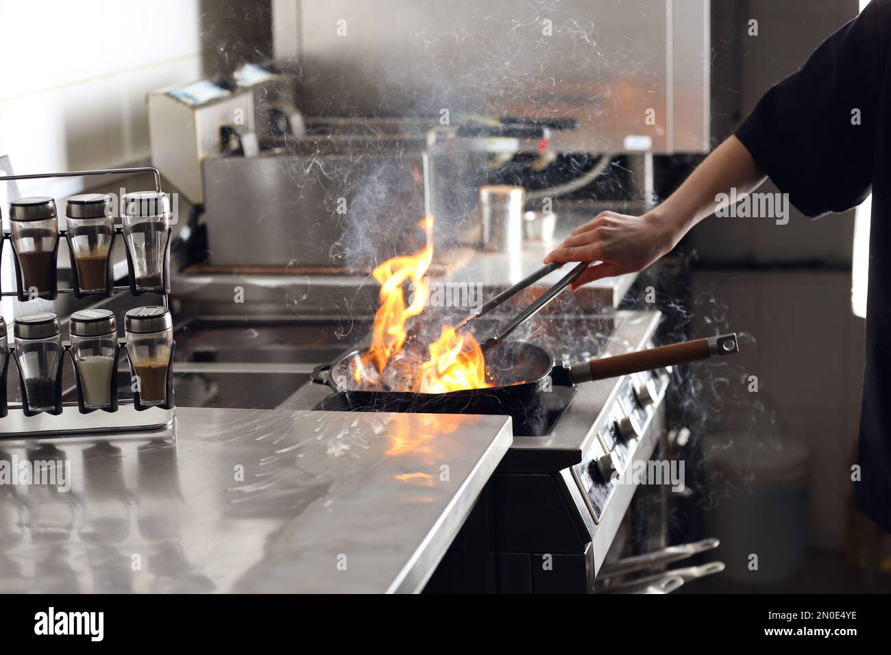 Female chef cooking meat with burning flame on stove in restaurant ...