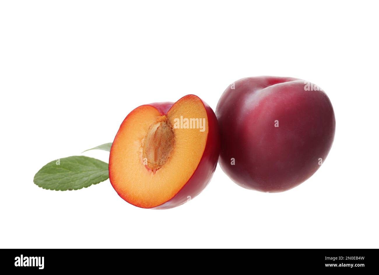 Whole and cut ripe plums with green leaves isolated on white Stock ...
