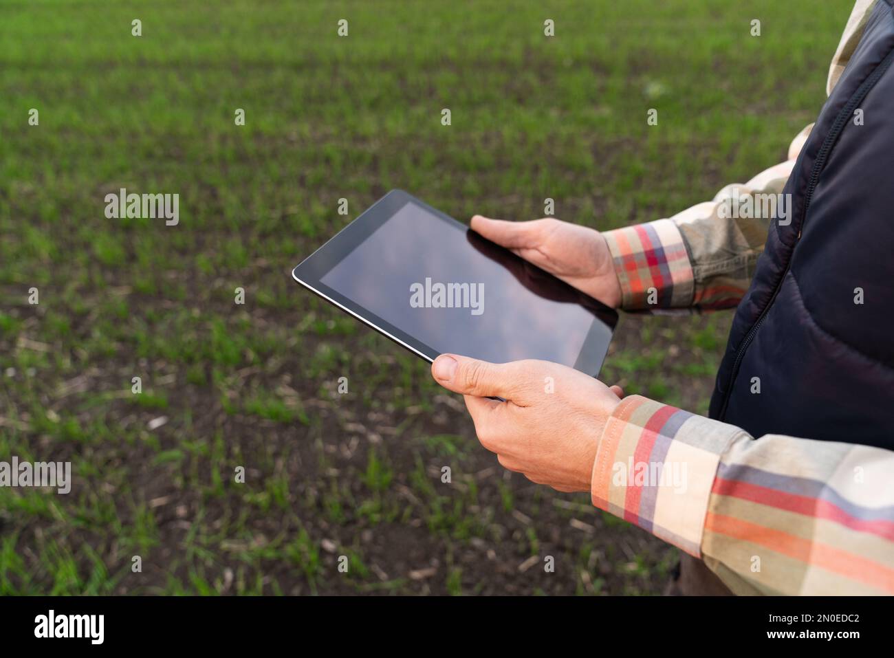 Farmer with digital tablet on an agricultural field. Close up. Smart farming and digital ...