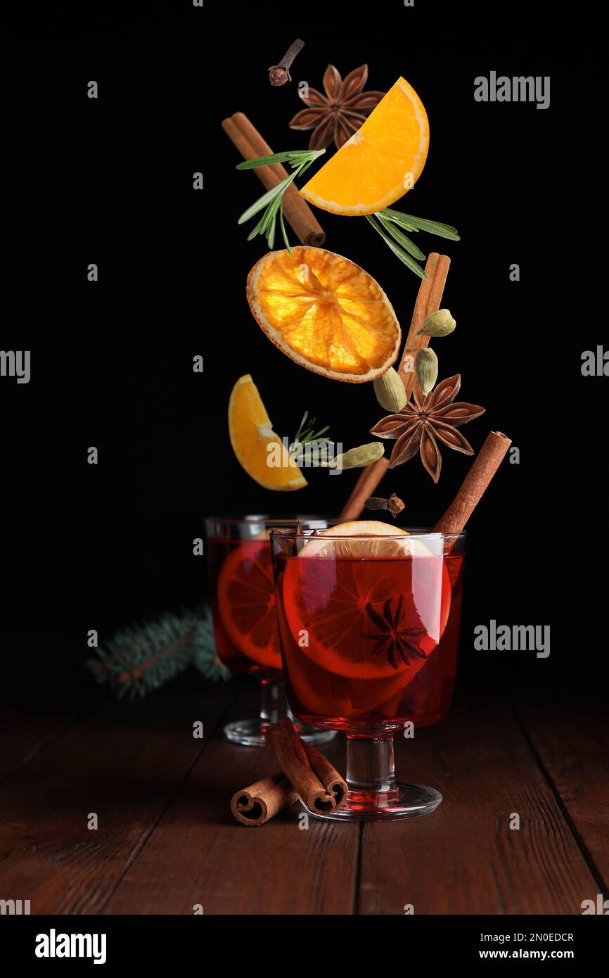 Cut orange and different spices falling into glass cups of mulled wine ...