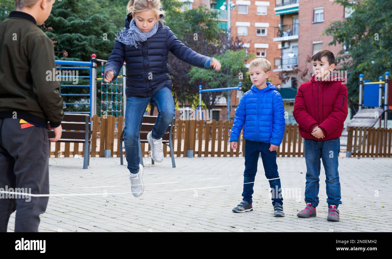 Kids skipping on chinese jumping elastic rope in yard Stock Photo - Alamy