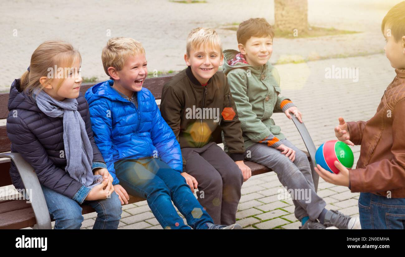 Kids playing with ball on bench Stock Photo - Alamy
