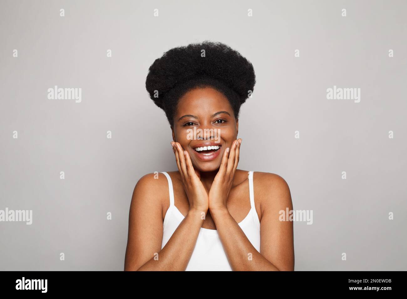 Happy beautiful woman holding her cheeks with a laugh looking at camera ...