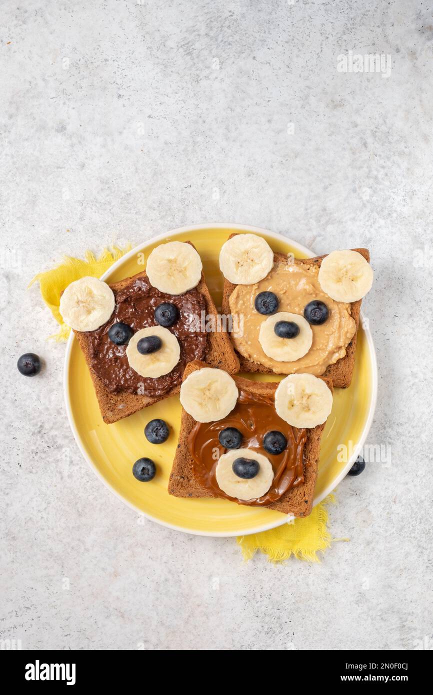 Breakfast toasts with nut butter and banana with cute funny bear face ...