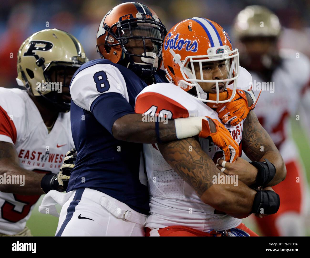 East linebacker Anthony Harrell (48), of Florida, is wrapped up by West ...