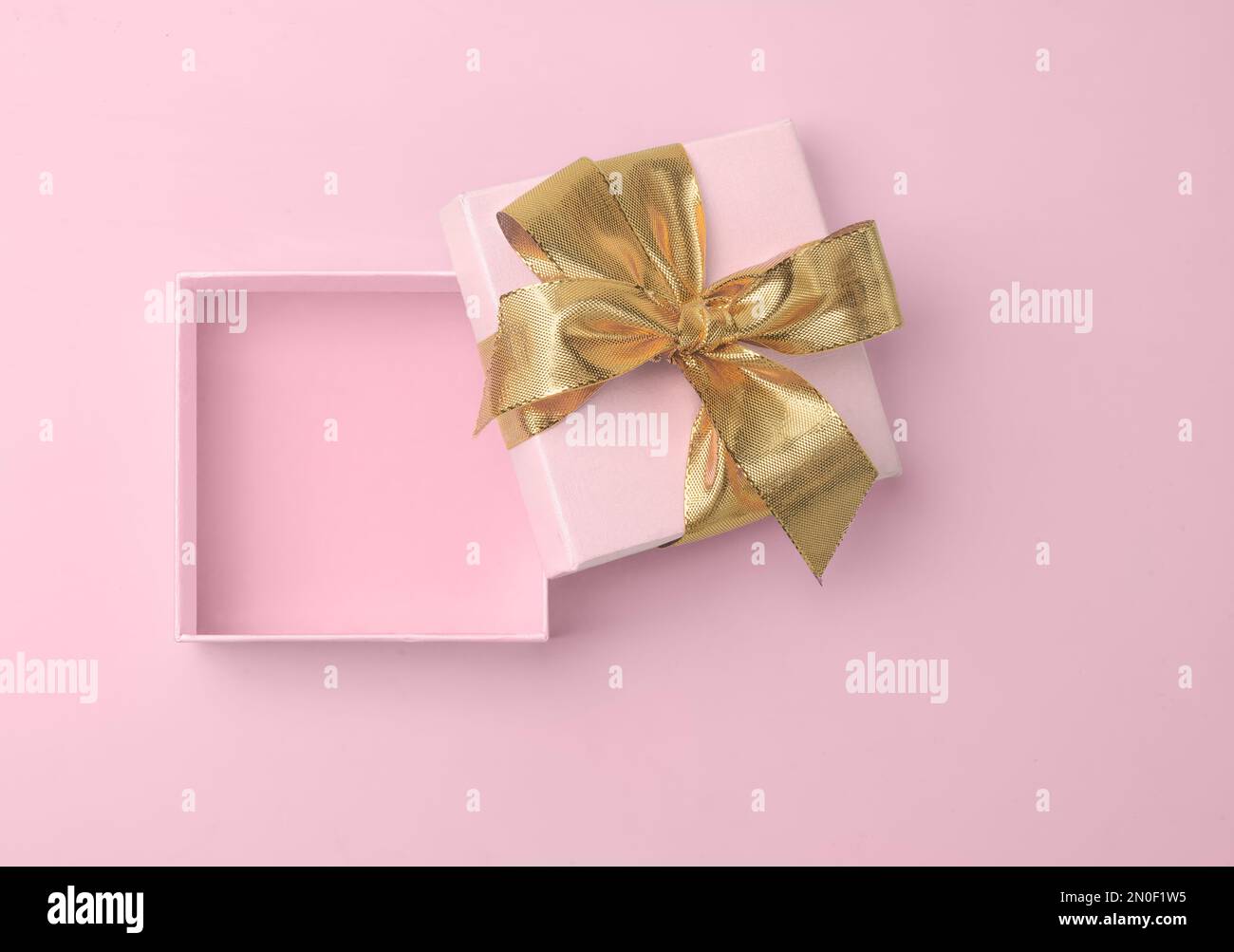 Pink empty gift box open with golden golden bow and ribbon Stock Photo ...