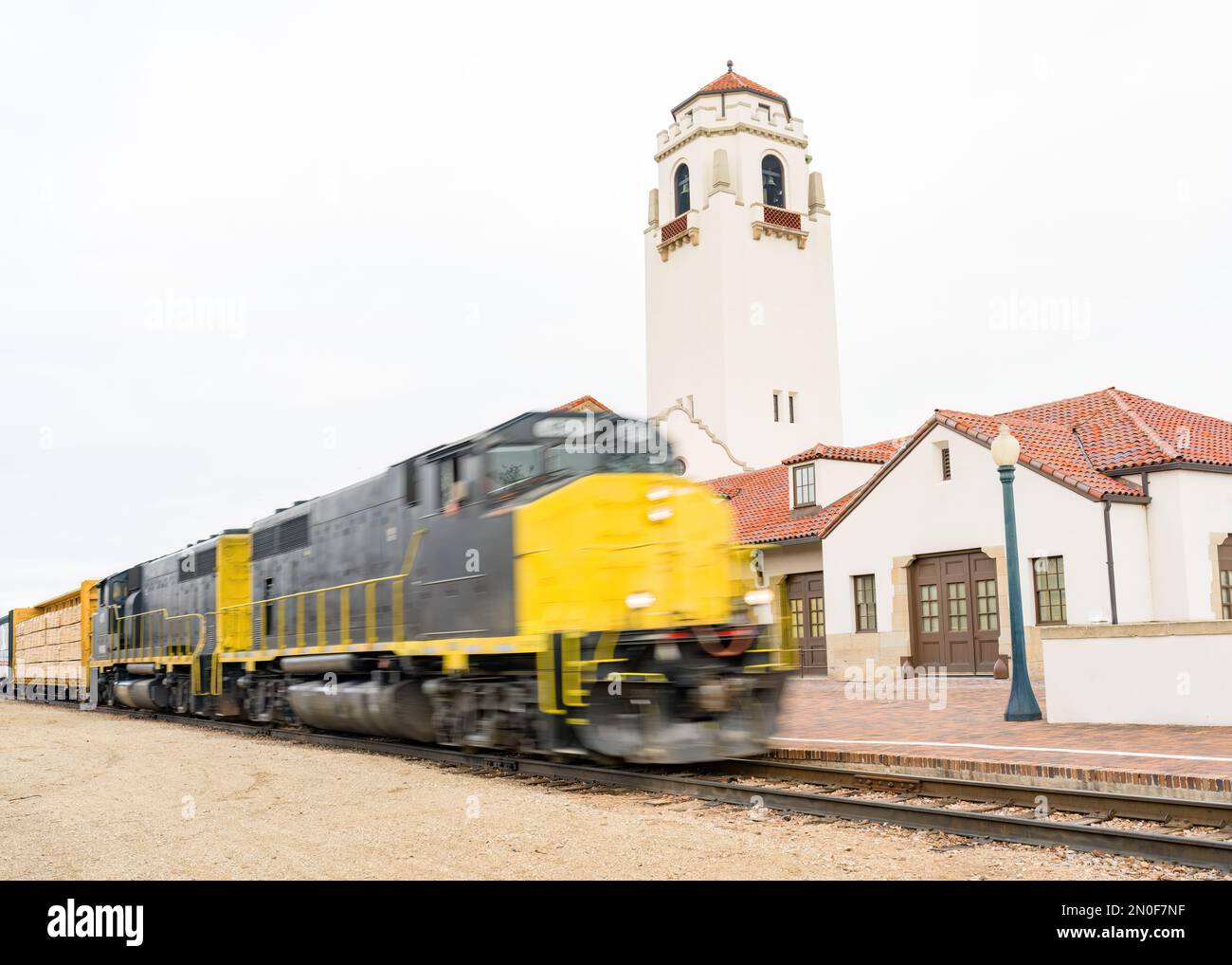 Yellow train engine and cars motion blur past train depot Stock Photo ...