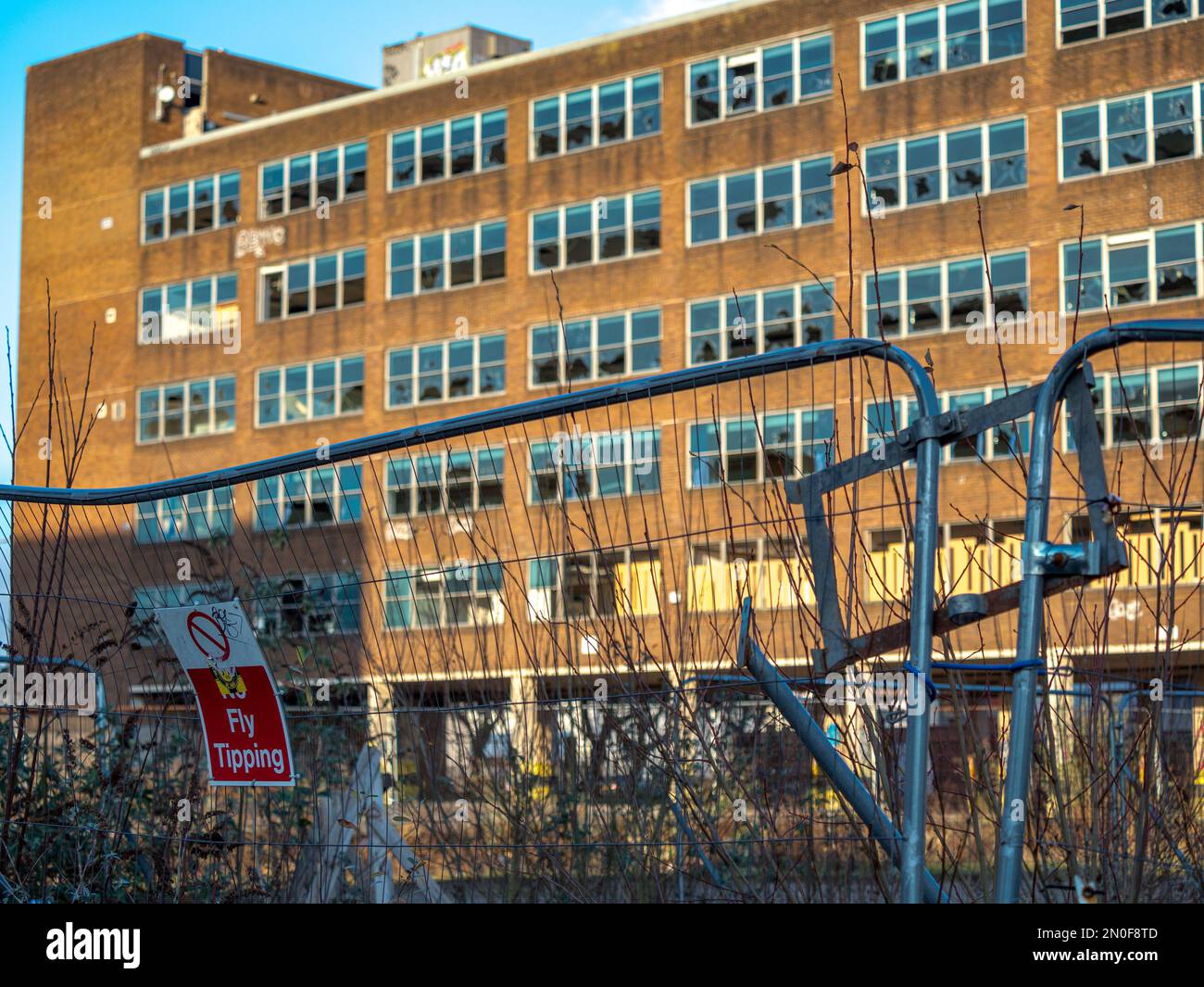 broken down security fencing with vandalized office block with broken ...