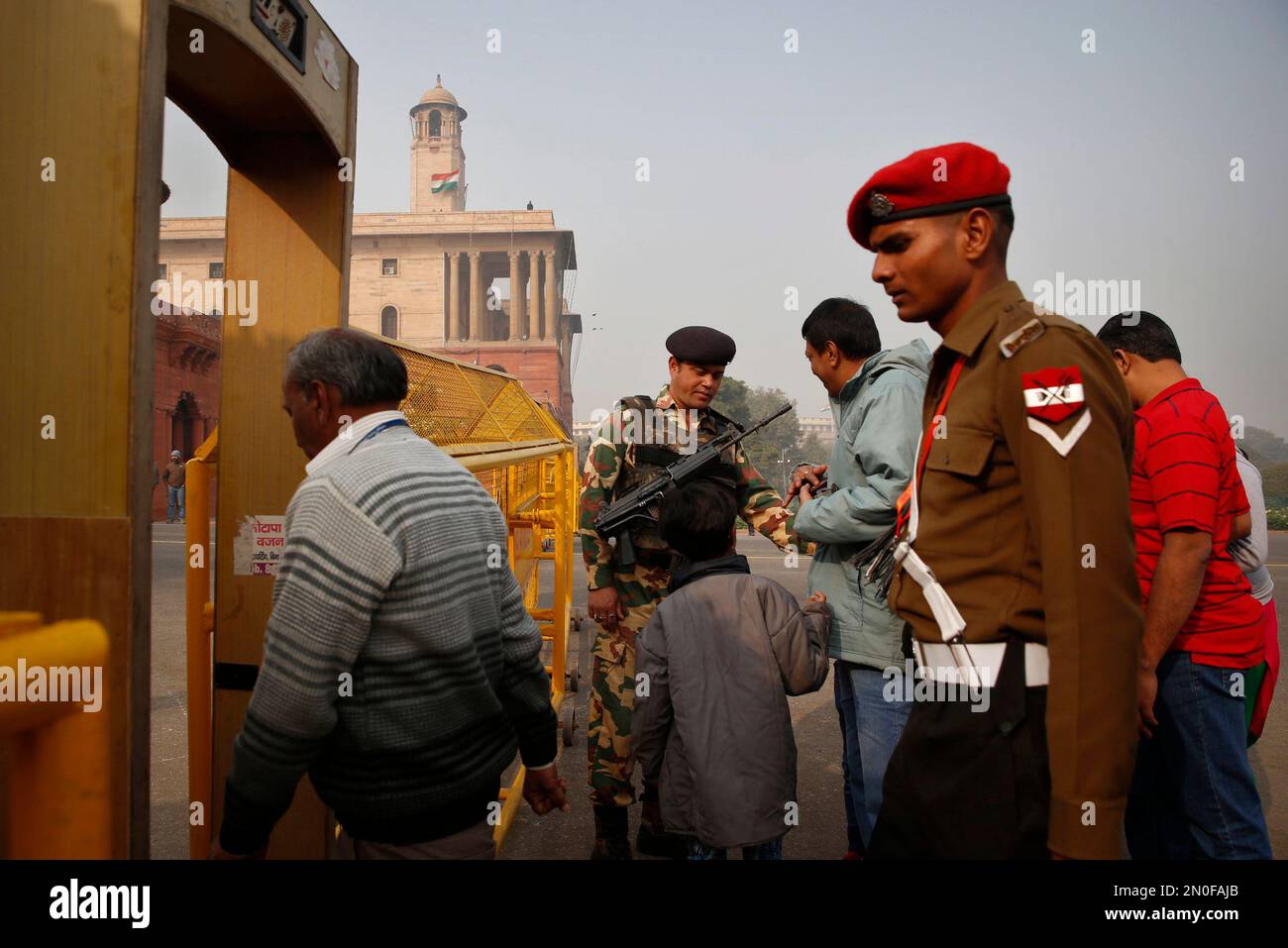 A man walks through a security gate as others are checked their ...