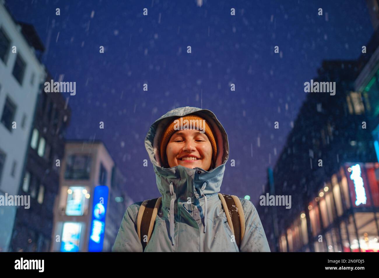 snowfall woman in a blue jacket and yellow hat christmas outside, city ...