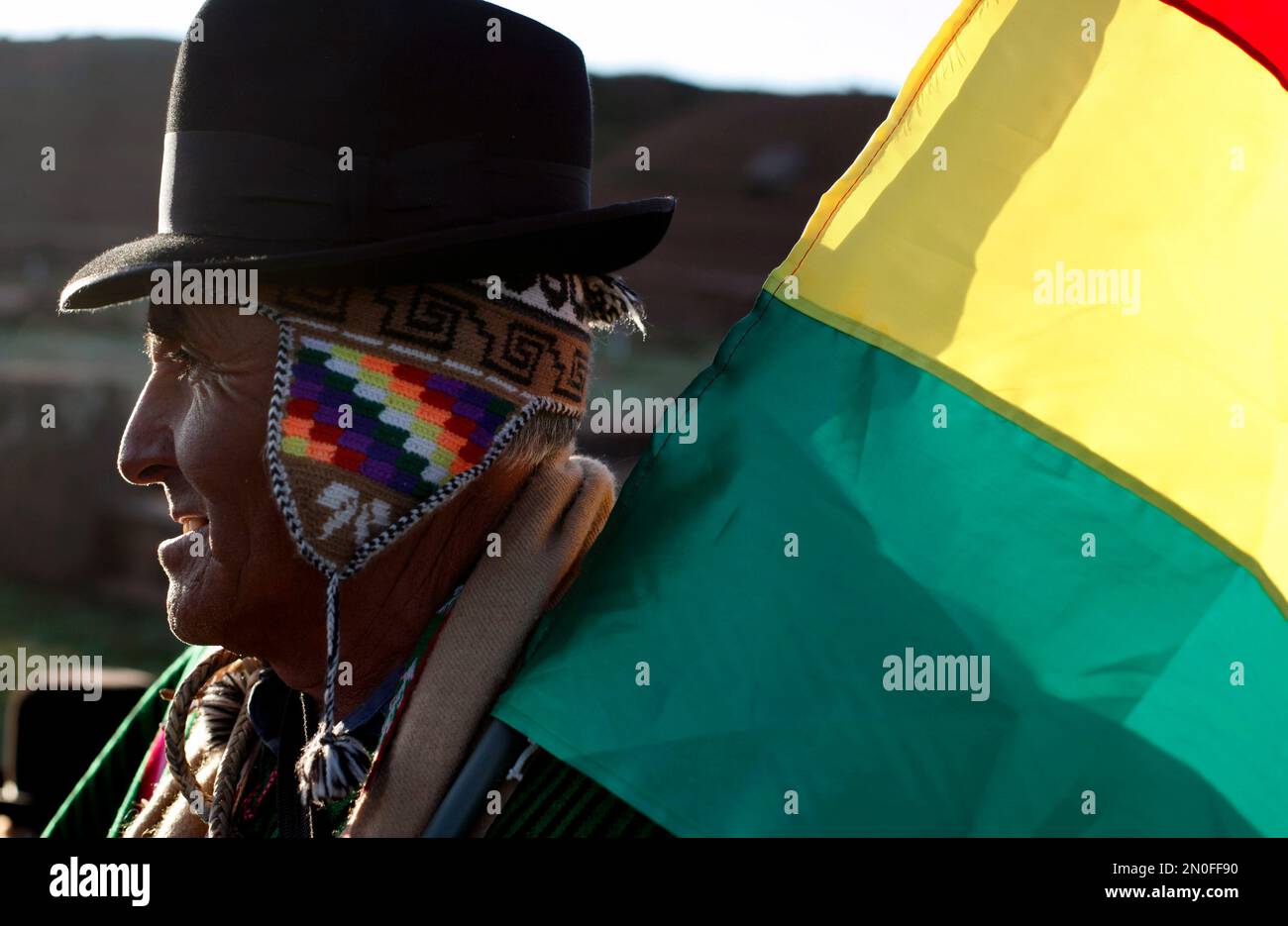 An Aymara man holding a representation of Bolivia's co-national flag ...
