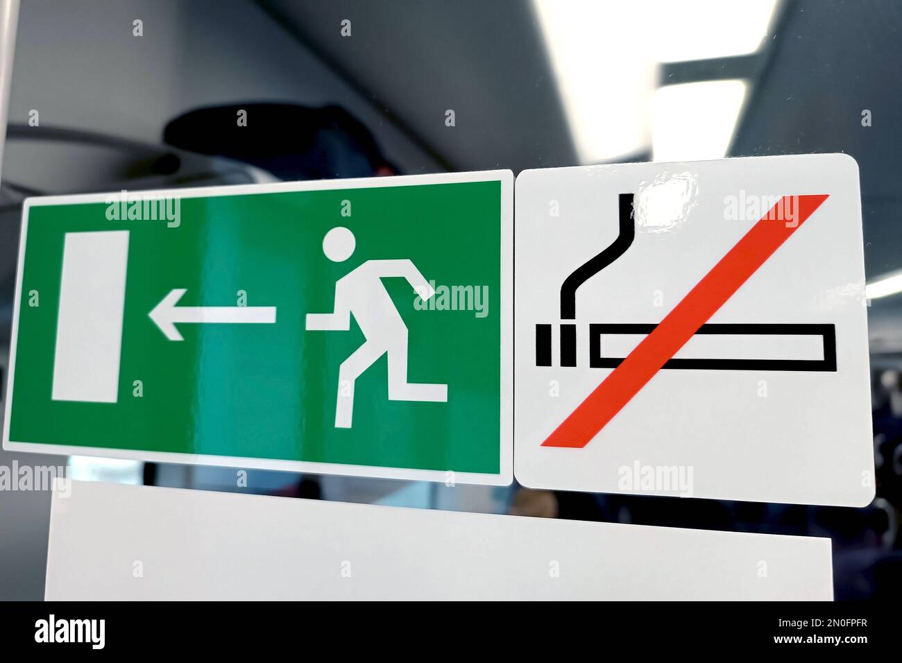 Green exit and no smoking signs near the door way in the train close up ...