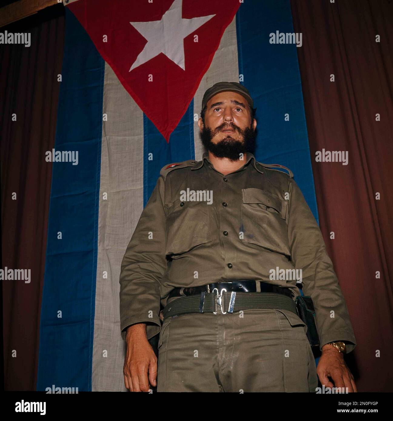Cuban Premier Fidel Castro stands in front of a Cuban flag, Aug. 10 ...