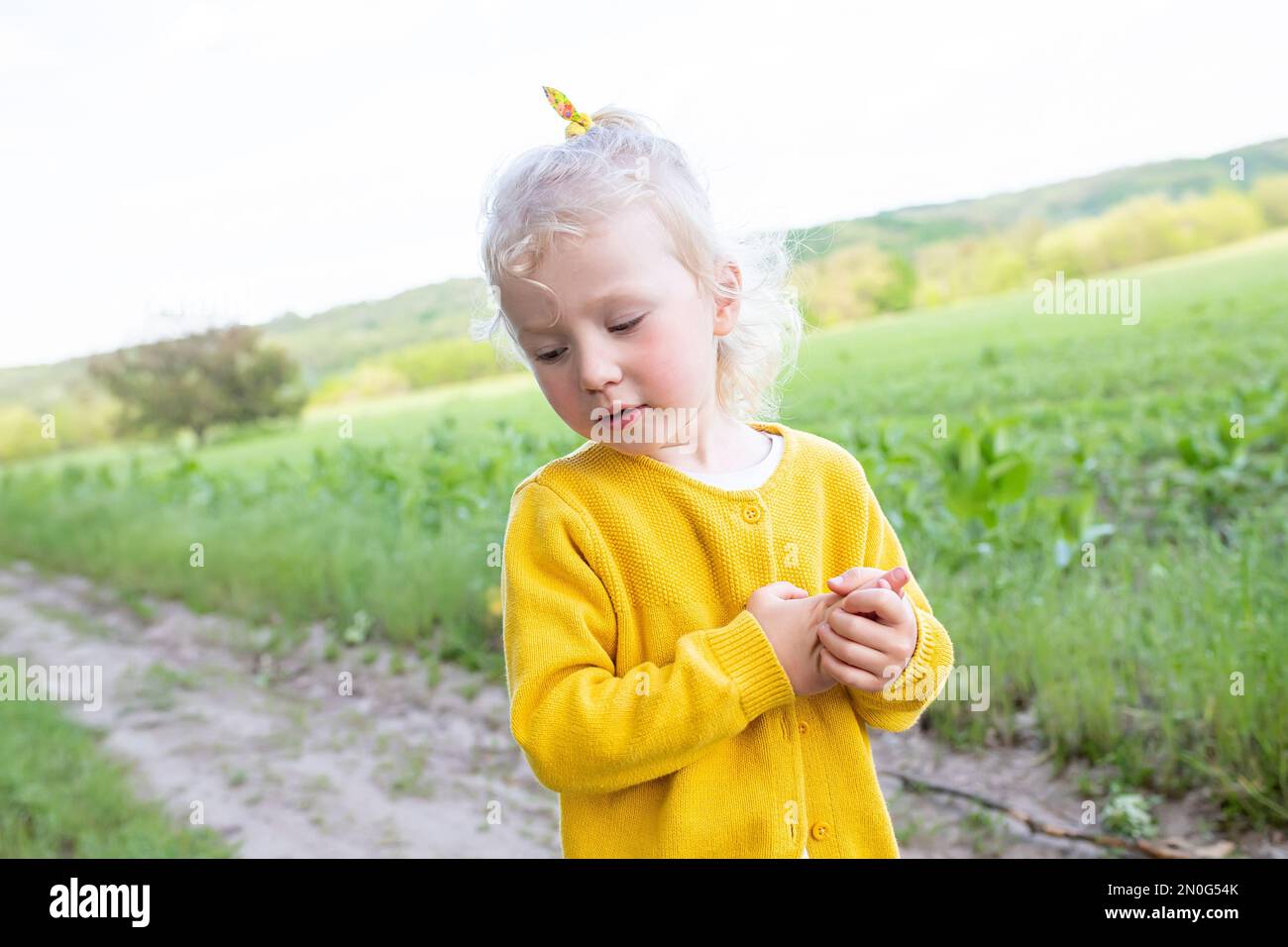 Sweet girl wrings hands and looks down. brooding child on background of ...