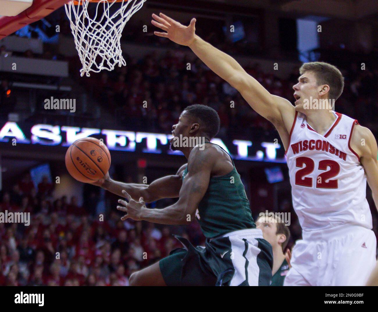 Michigan State's Eron Harris, left, shoots past Wisconsin's Ethan Happ ...