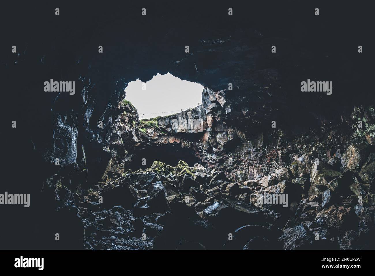 Cave with opening and light coming through. Walking through lava cave ...