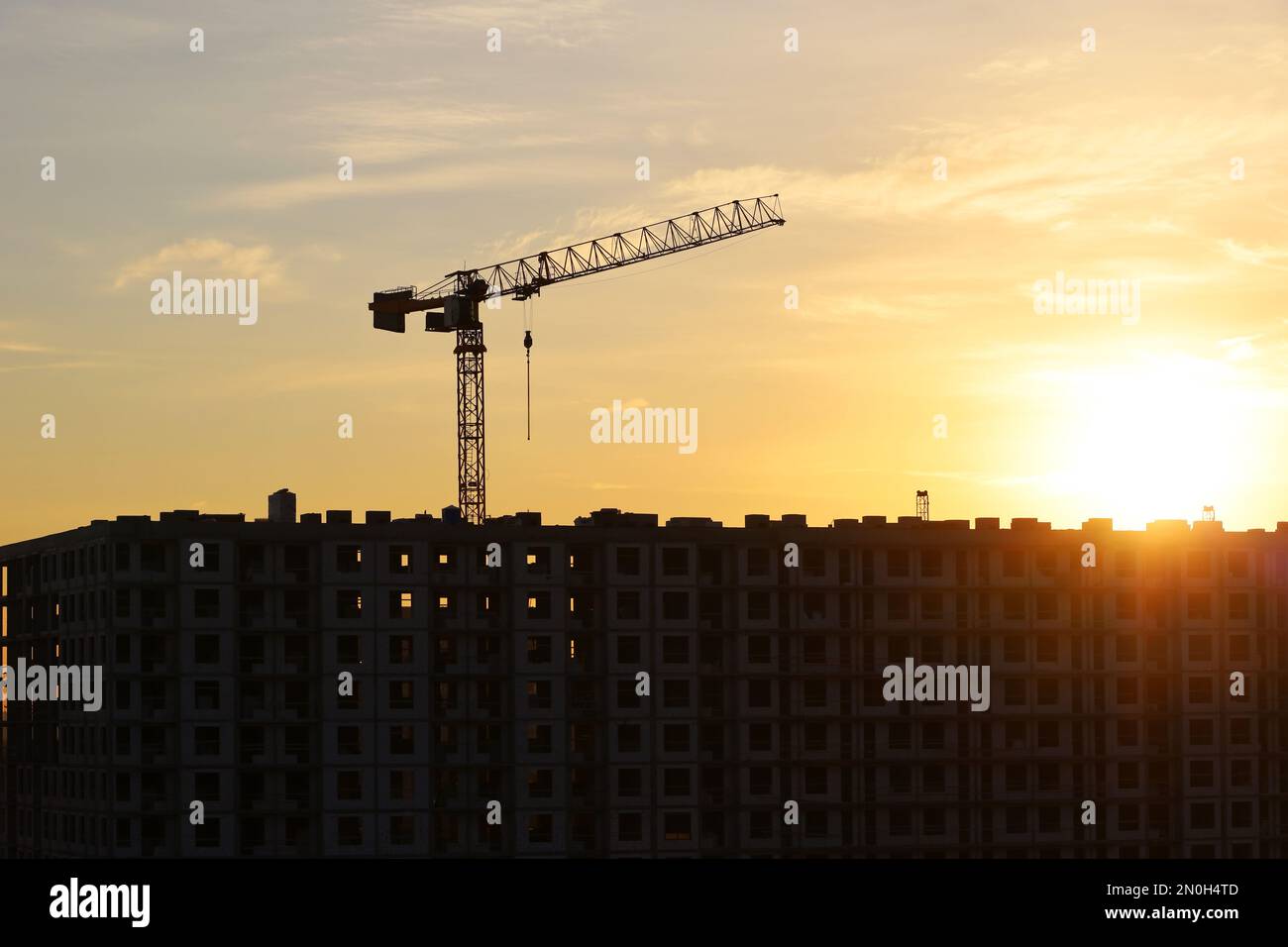 Silhouette of tower crane and scaffolding of unfinished building at ...